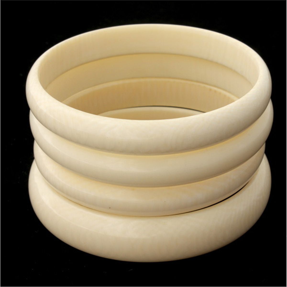 COLLECTION OF FOUR CARVED IVORY BANGLES.