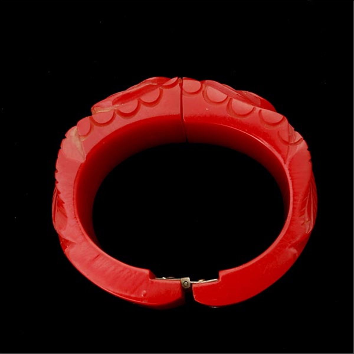 RED CARVED BAKELITE HINGED BANGLE BRACELET.