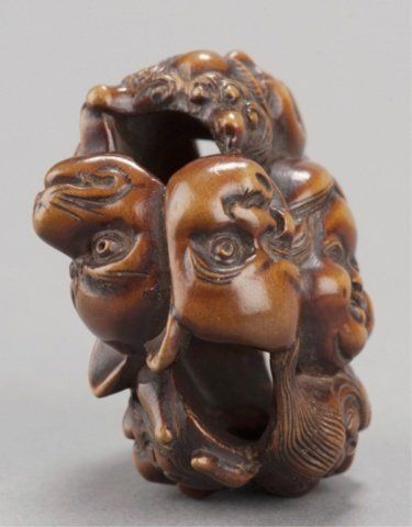 A wood ryusa netsuke of group of nine Noh masks.
