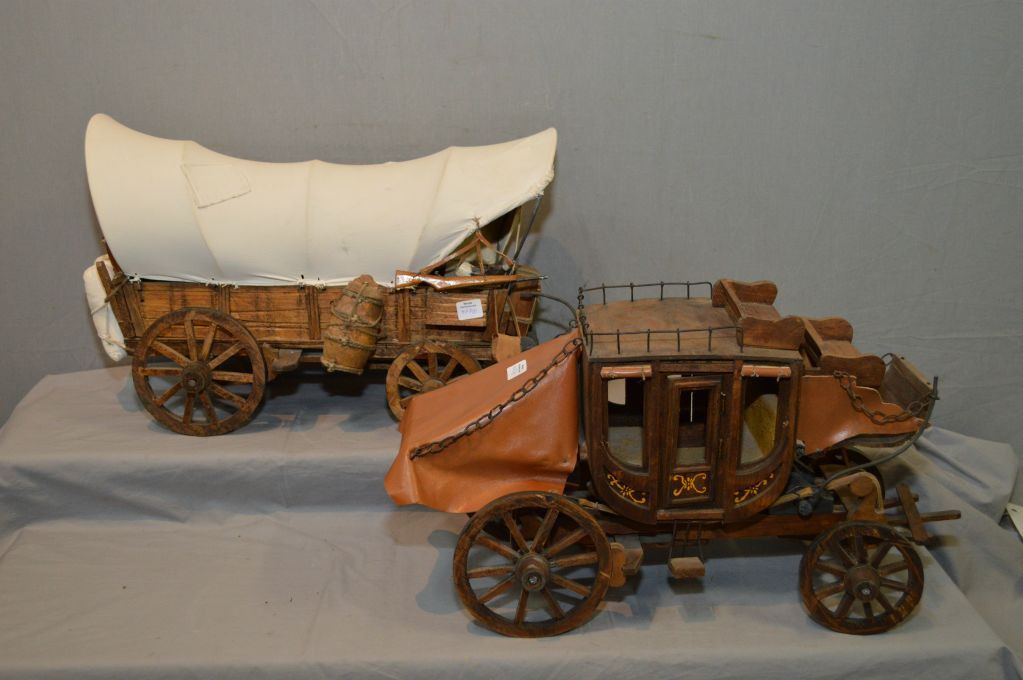 Two wooden decor replicas including a covered wagon and a stagecoach