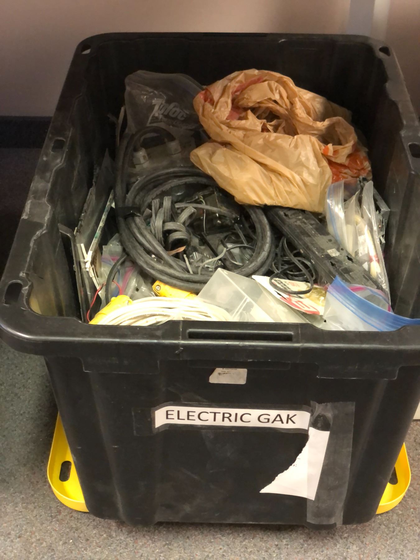 Black plastic storage bin filled w/ electrical misc.